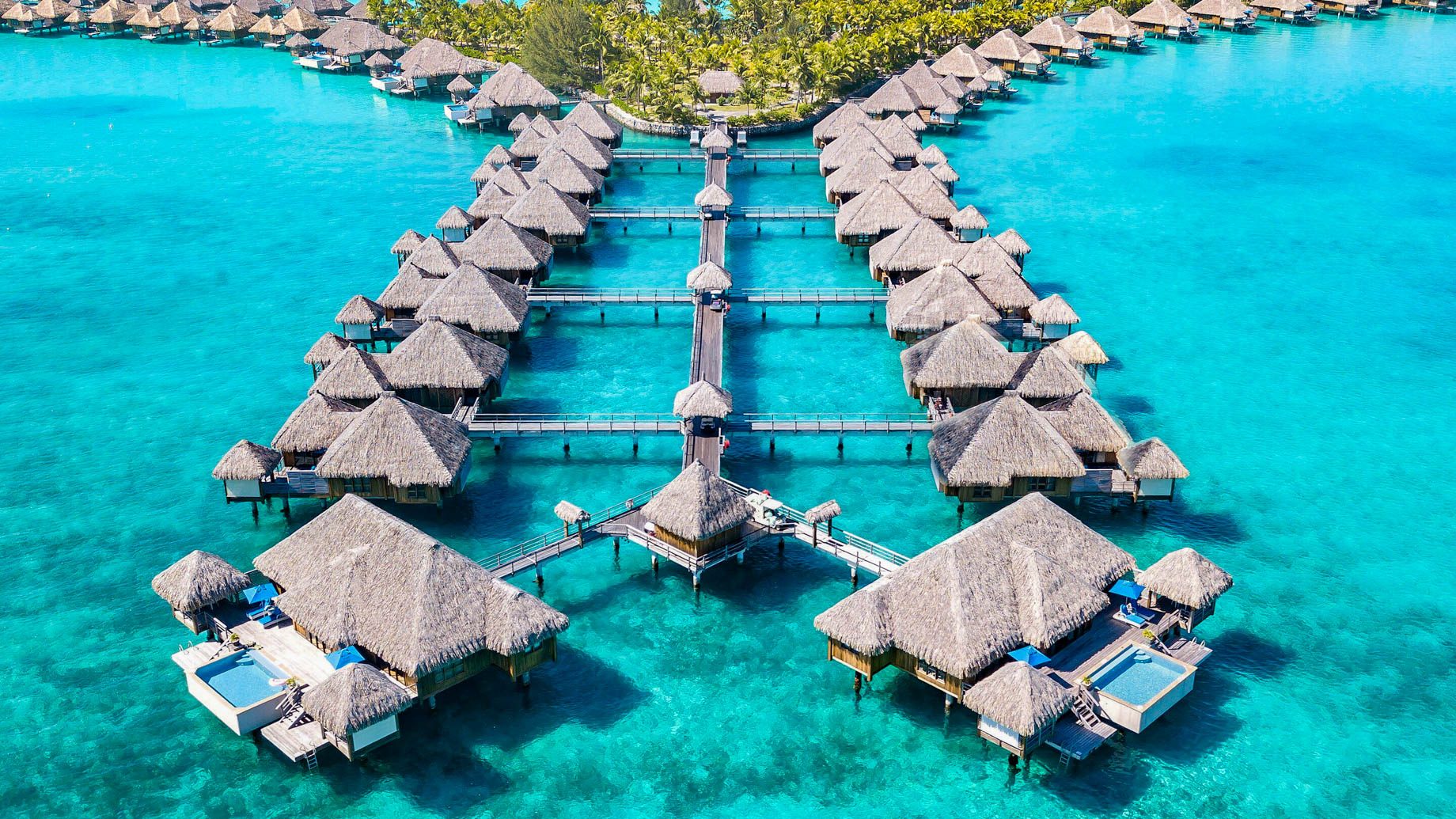 Resort units above shallow turquoise waters in the Maldives – TRAVOH